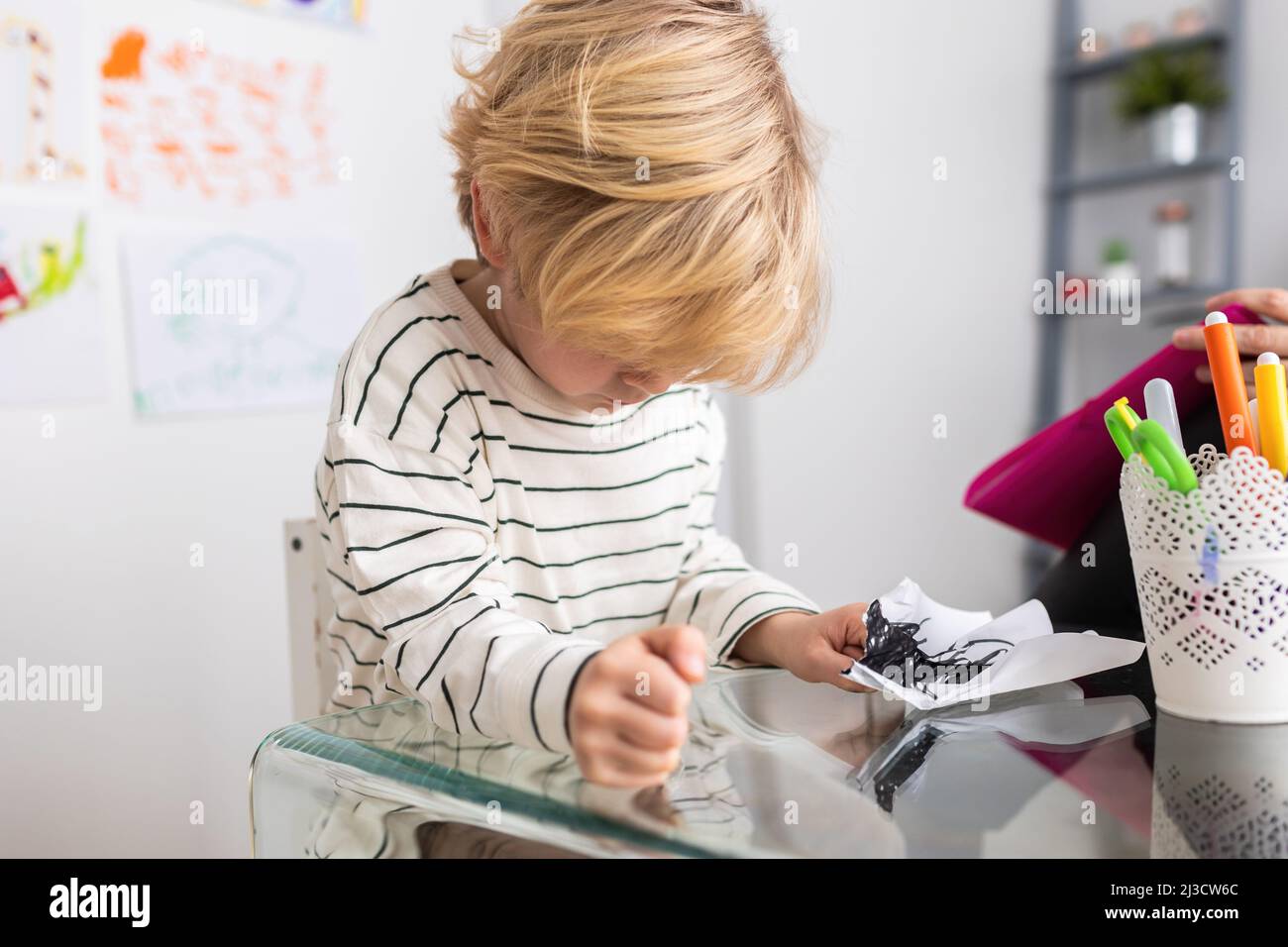 Unhappy boy tearing up drawing with black strokes while sitting at ...