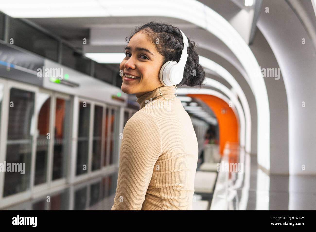 Side view of happy Colombian female passenger listening to songs from ...