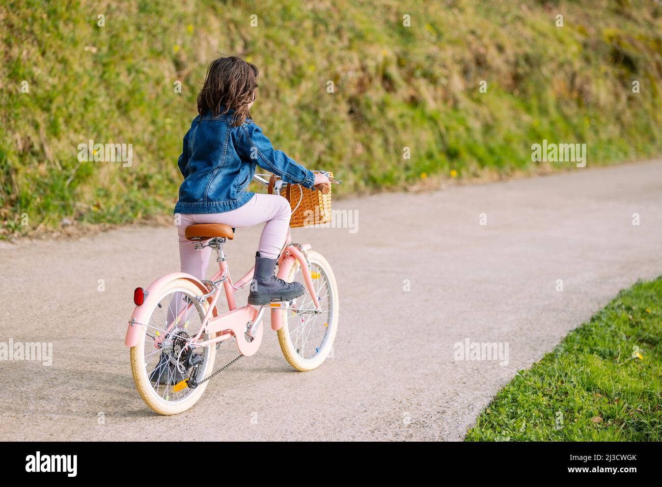 Full body bach view of unrecognizable kid in denim jacket riding ...