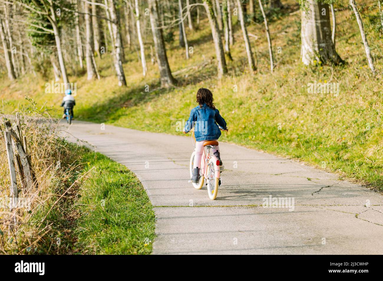 Full body back view of unrecognizable kid in denim jacket riding ...