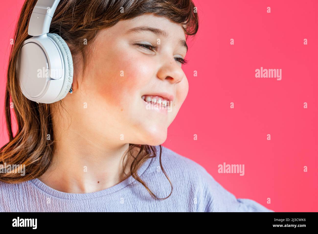 Cheerful girl laughing while enjoying music in headphones against ...