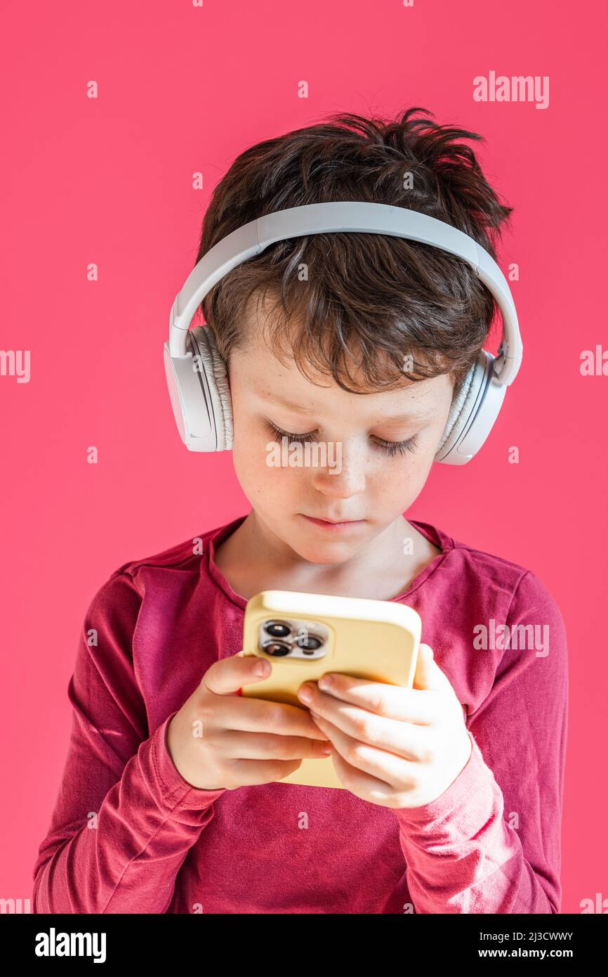 Serious boy listening to music in headphones and browsing modern ...