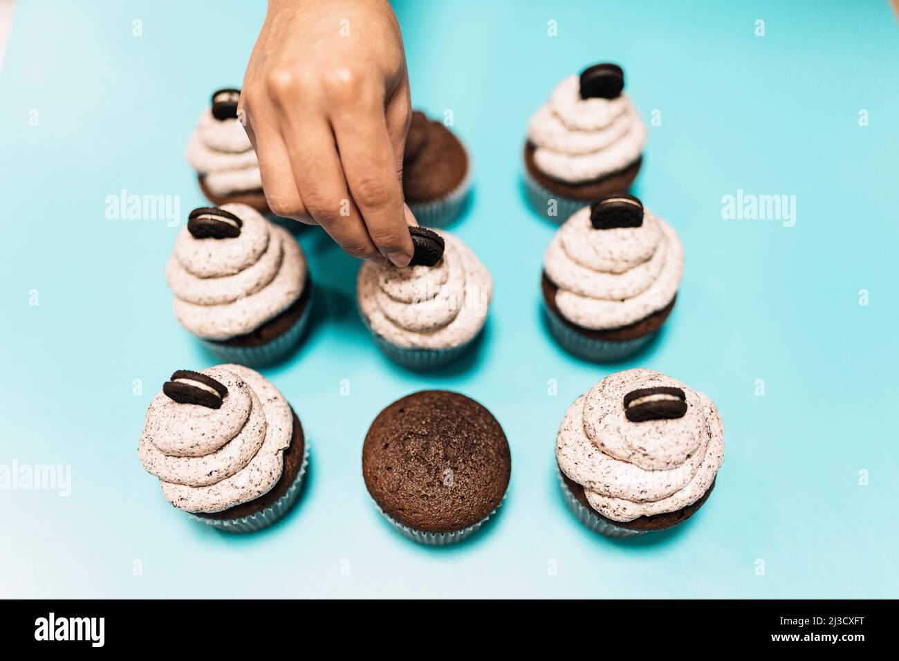 From above anonymous Woman putting tiny biscuit on top of fresh cupcake ...