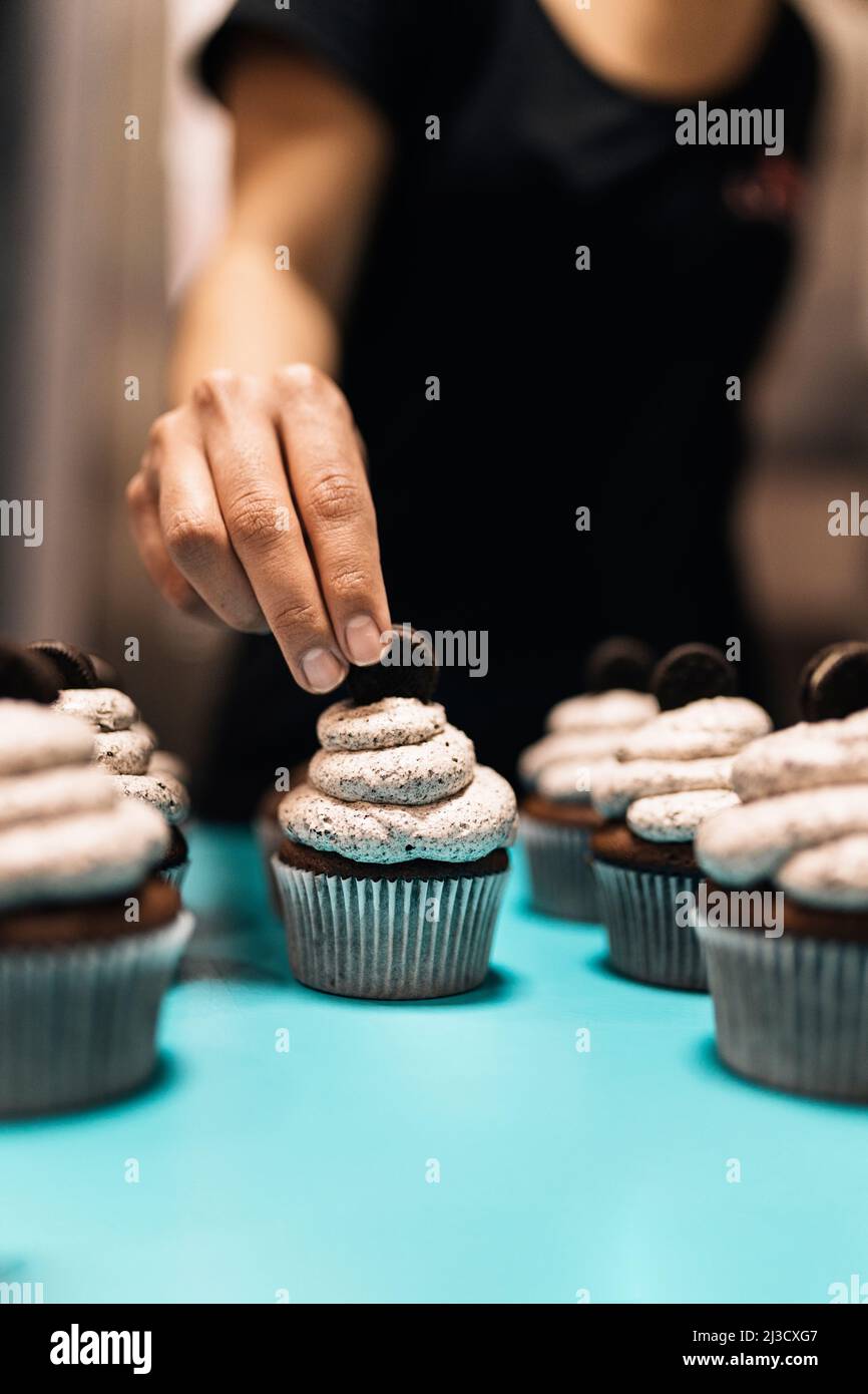 Anonymous Woman putting tiny biscuit on top of fresh cupcake on blurred ...