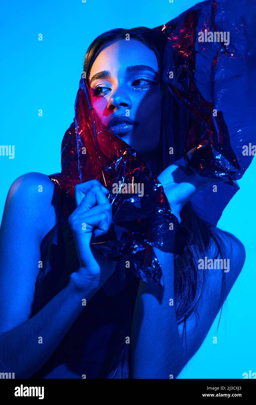 Confident female model wrapped in plastic film standing in provocative ...