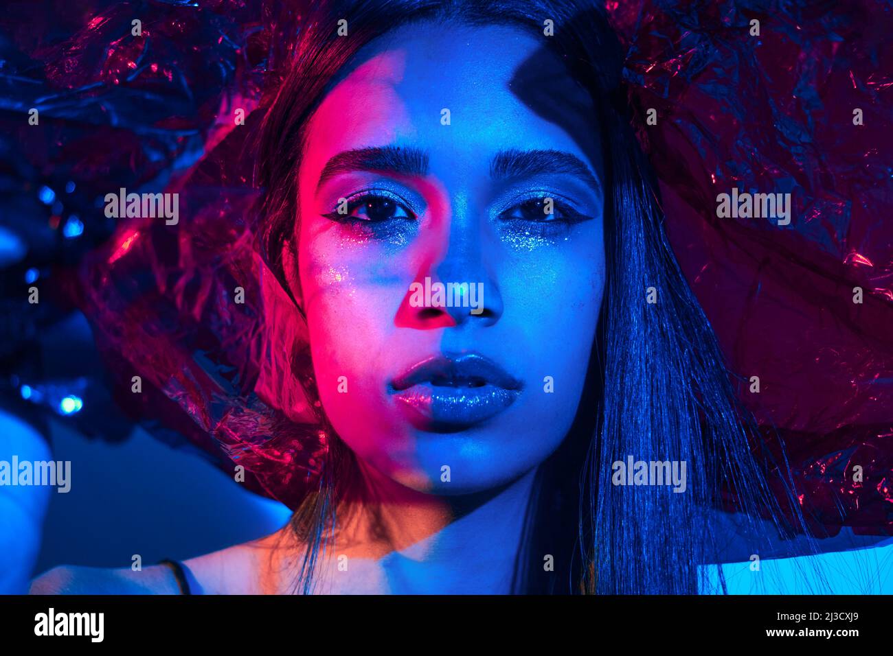 Confident female model wrapped in plastic film standing in studio with ...