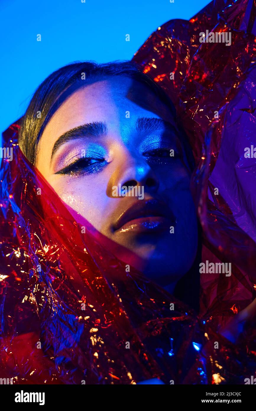 Confident female model wrapped in plastic film standing in studio with ...