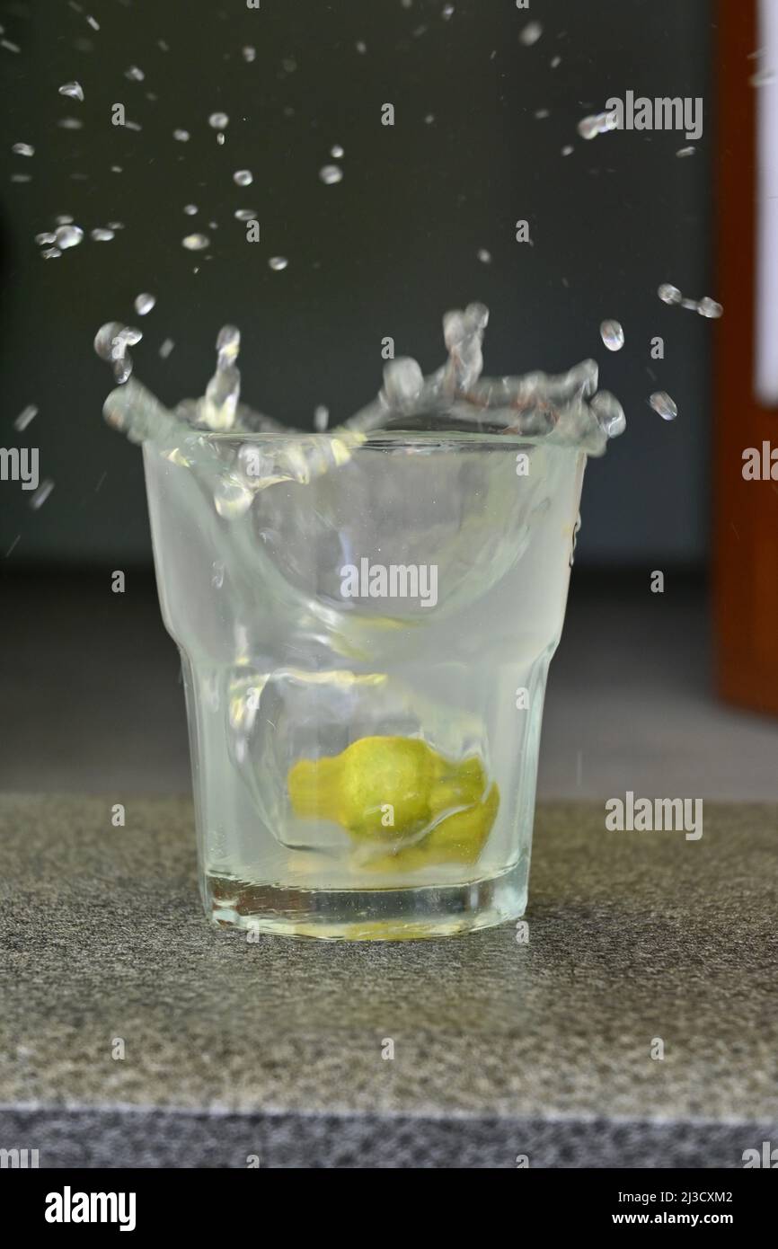 closeup the lemon juice flow in the glass over out of focus grey brown ...