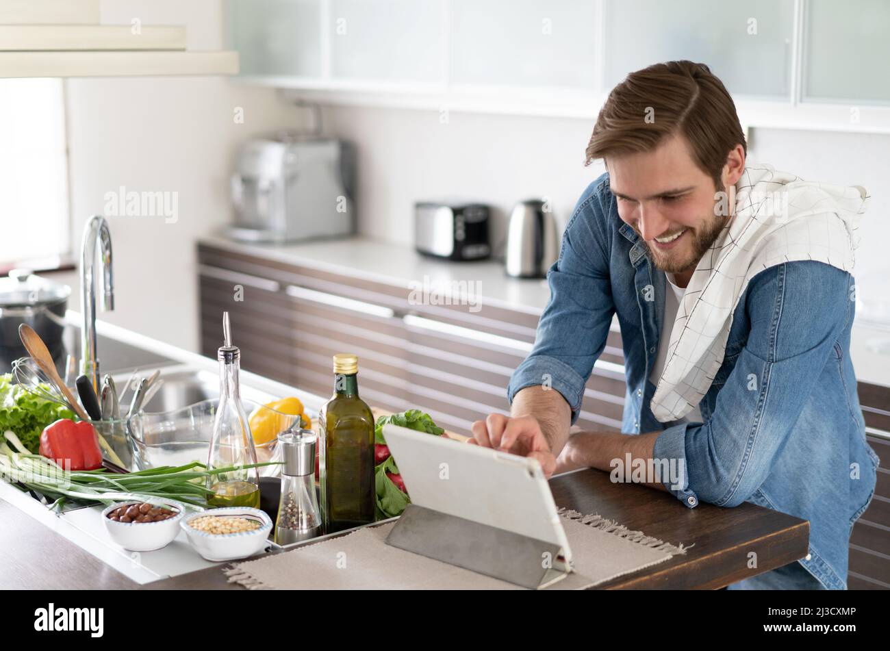 cooking, technology and home concept - man reading recipe from tablet ...