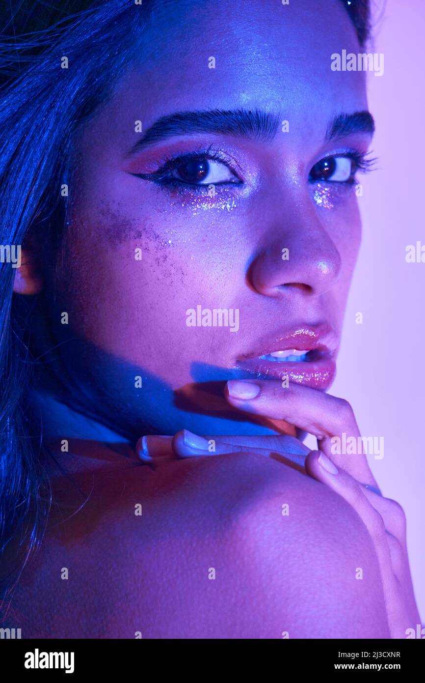 Charming young female model with shiny glitter makeup in studio with ...