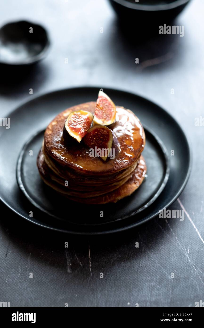 From above stack of yummy pancakes with maple syrup and fig slices ...