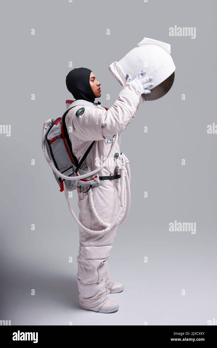 Side view of astronaut in spacesuit taking off protective helmet with ...