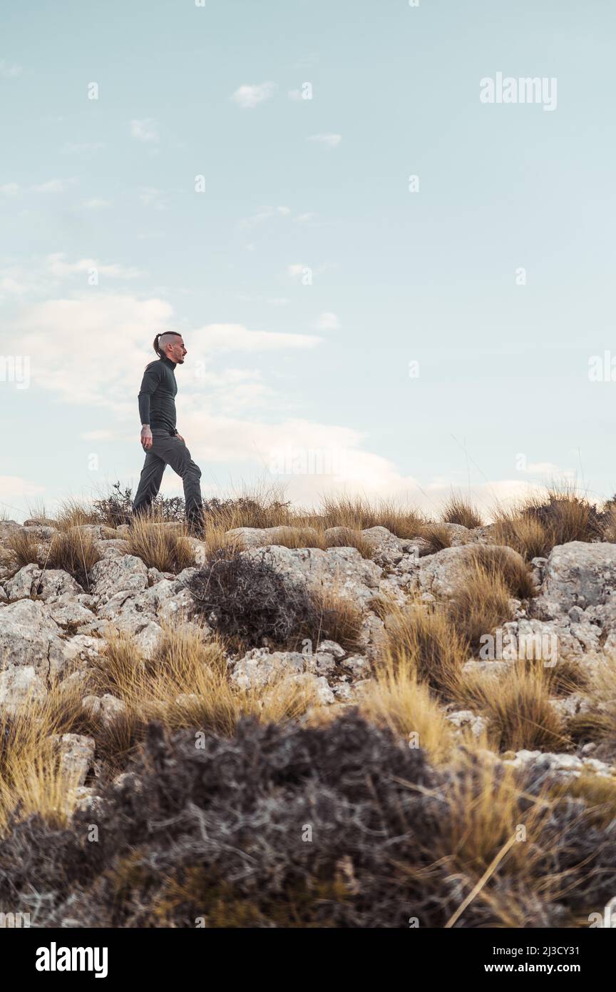 Full body side view of male explorer standing with hand on waist on ...