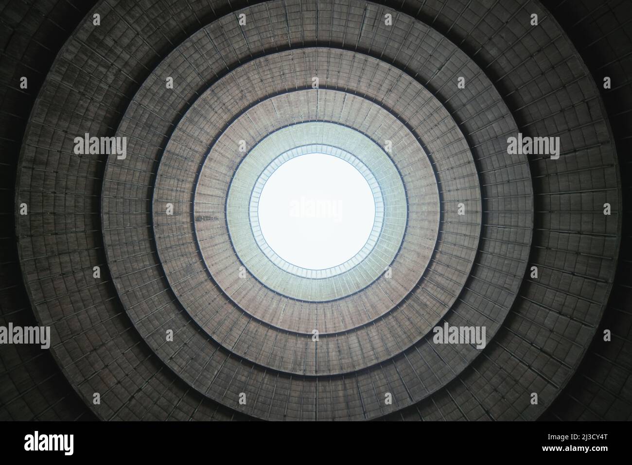 From below sunlight shining through round hole in ceiling of industrial ...