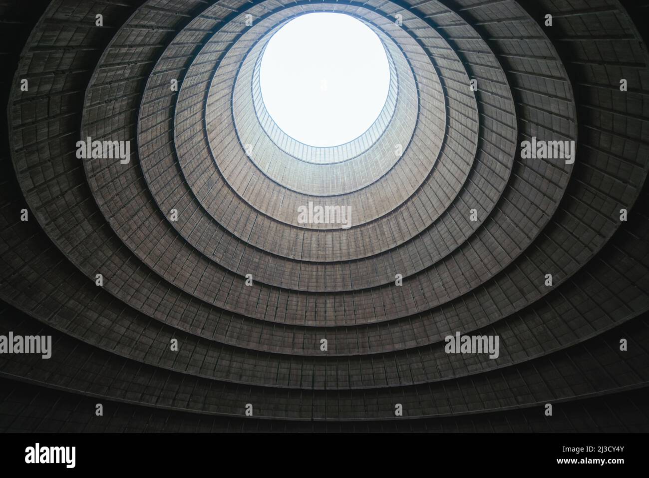 From below sunlight shining through round hole in ceiling of industrial ...