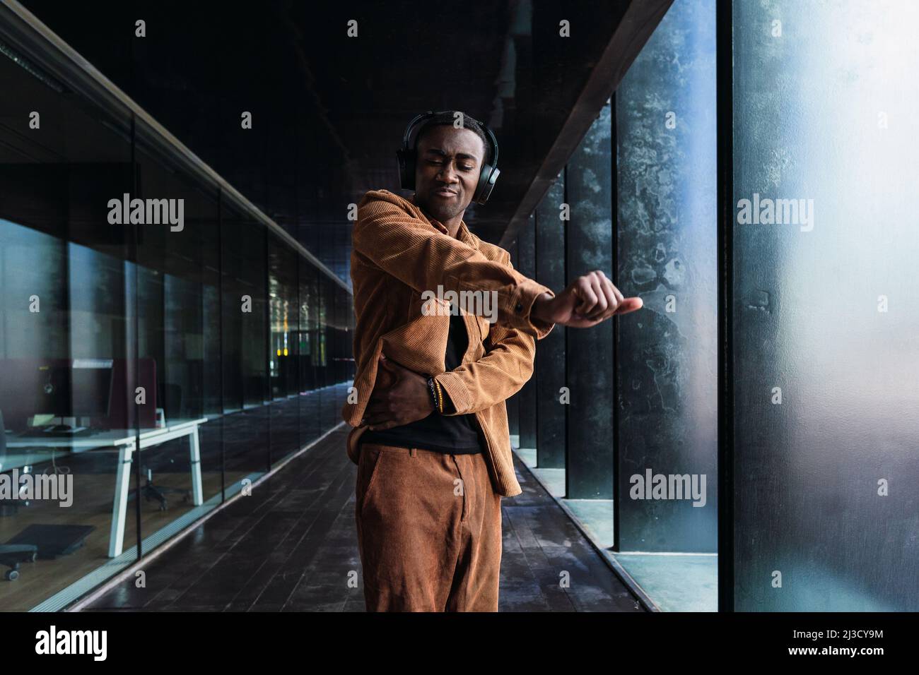 Stylish African American male dancing and listening to music in ...