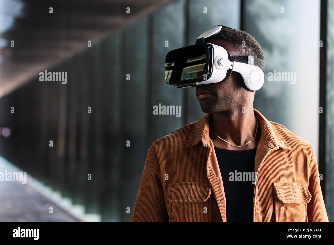 Positive African American male in modern VR goggles standing near glass ...