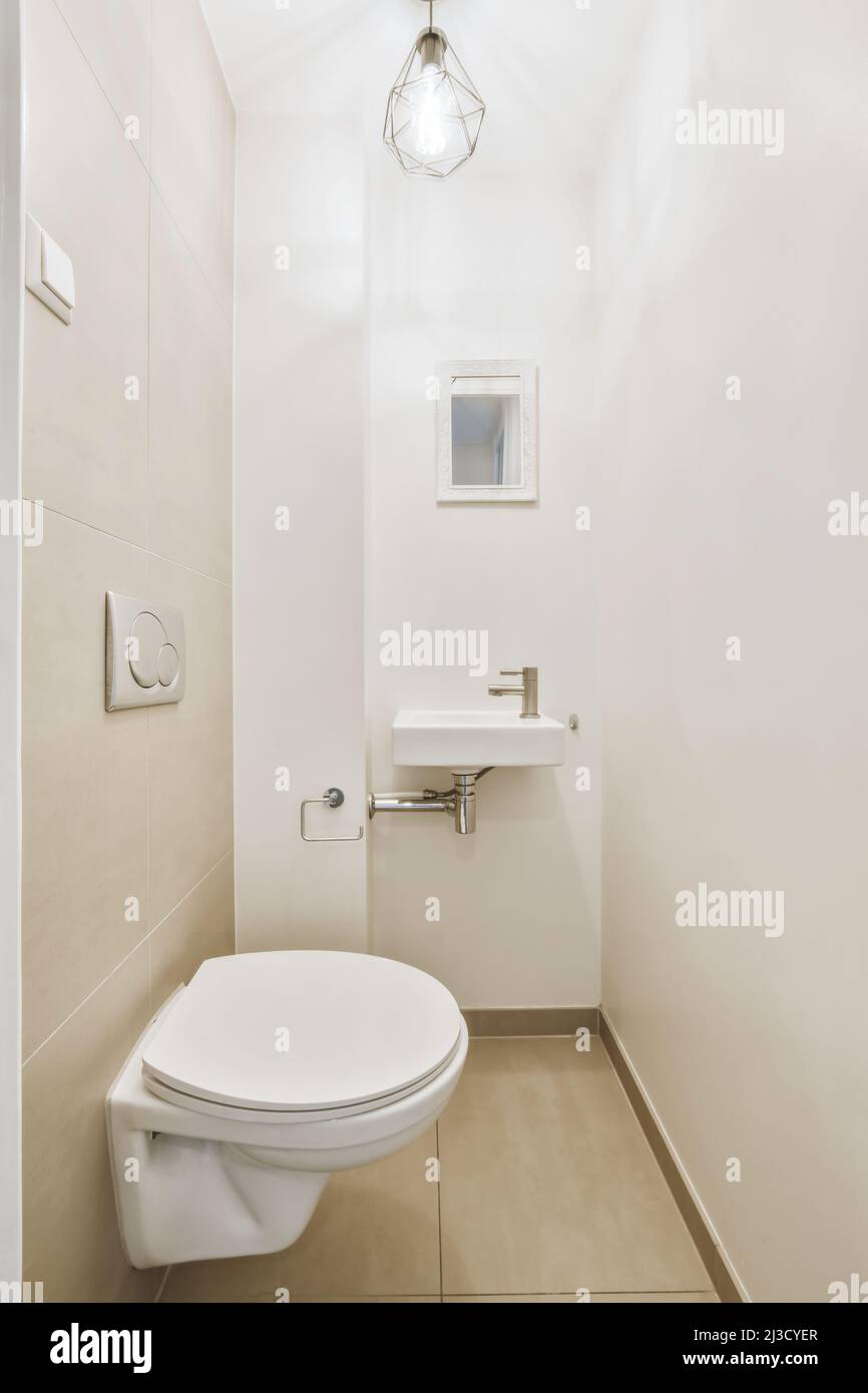 Toilet placed at wall in light small bathroom with a window at home ...