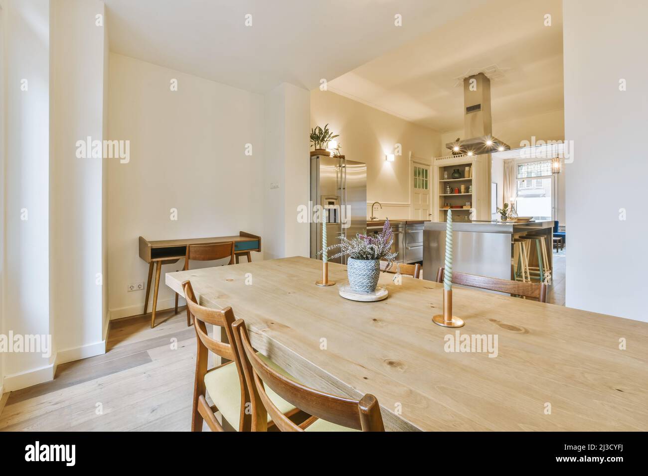 Wooden table with candles placed in light spacious kitchen with counter ...