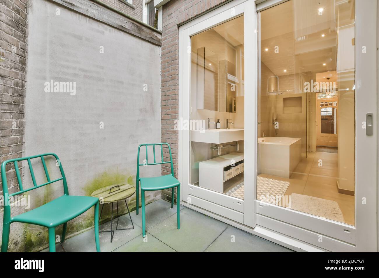 Terrace with turquoise chairs placed at wall near glass door of ...