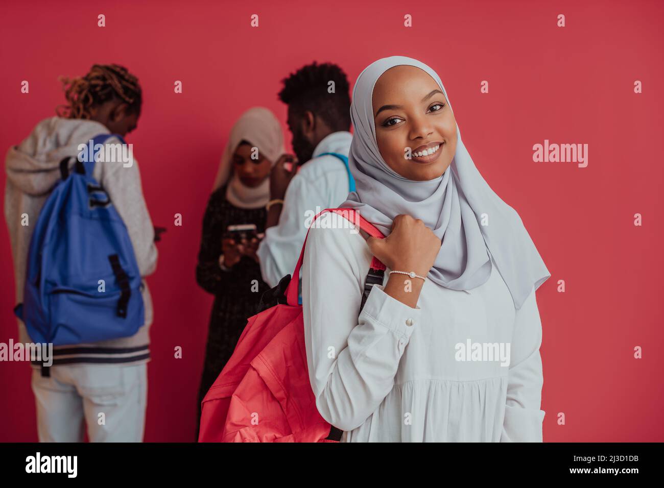 A group of African Muslim students with backpacks posing on a pink ...