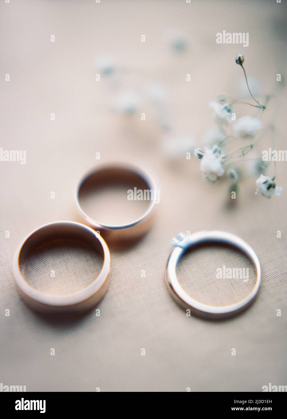 Rustic wedding. Golden wedding rings and engagement ring on beige ...