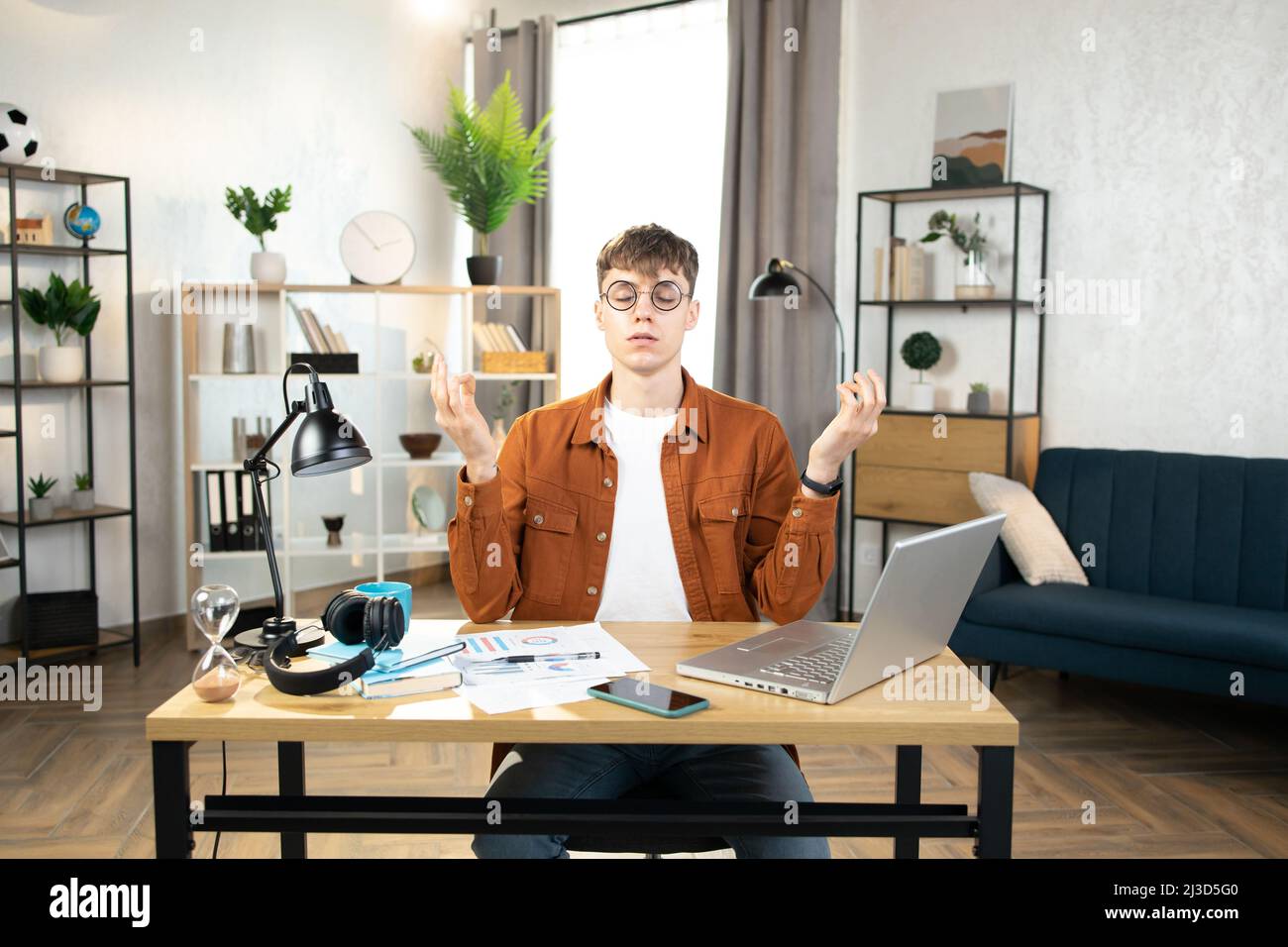 Relaxed young man in casual wear sitting on workplace with modern ...