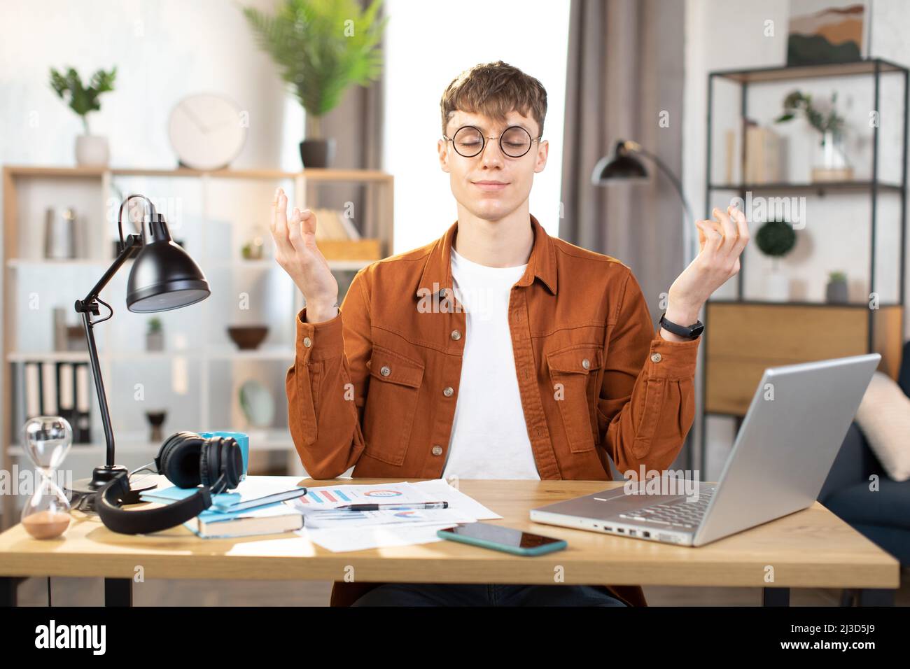 Relaxed young man in casual wear sitting on workplace with modern ...