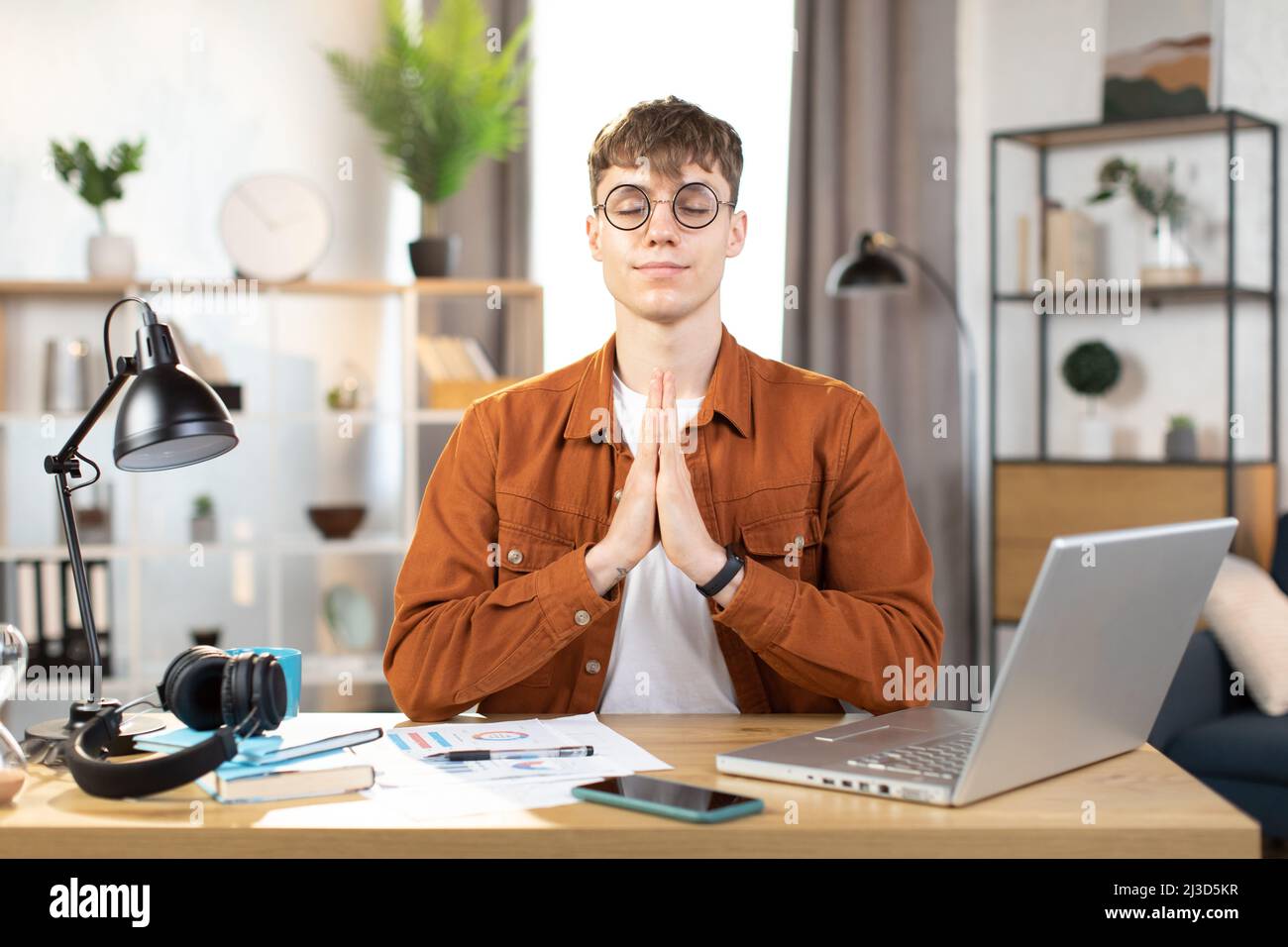 Relaxed young man in casual wear sitting on workplace with modern ...