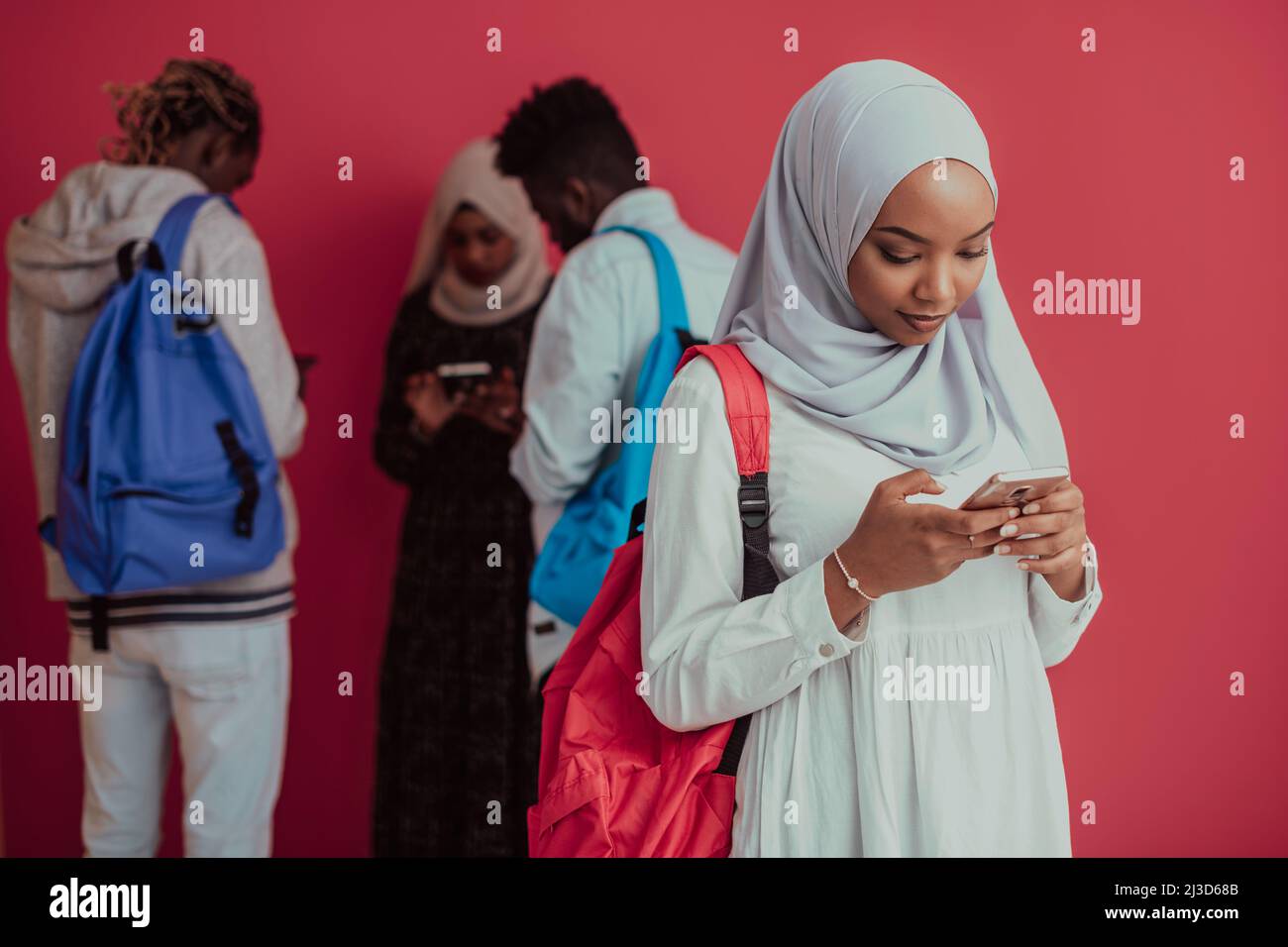 A group of African Muslim students with backpacks posing on a pink ...