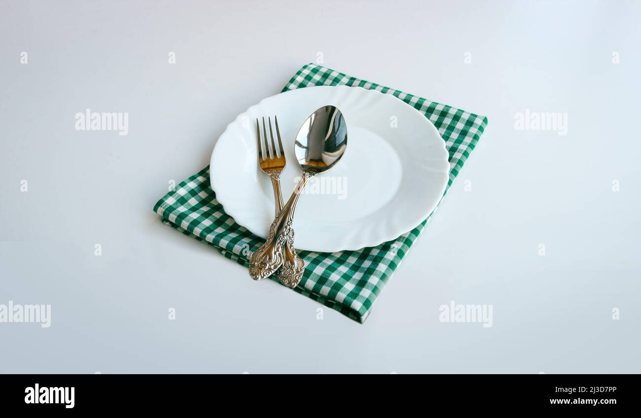 White plate, cutlery and checkered doily on a light background Stock ...