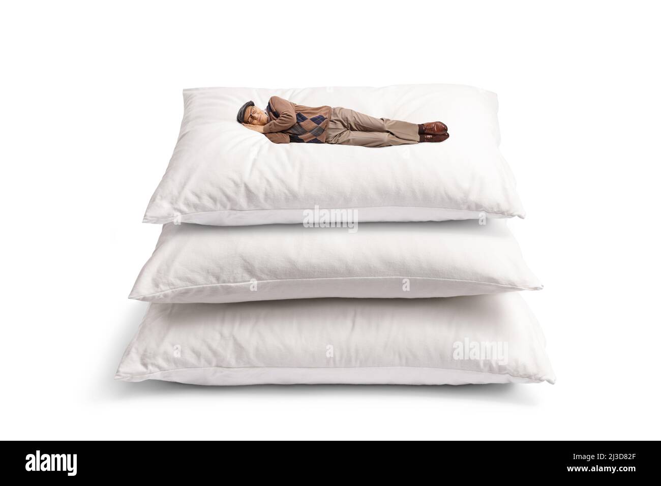 Edlerly man sleeping on a pile of pillows isolated on white background ...