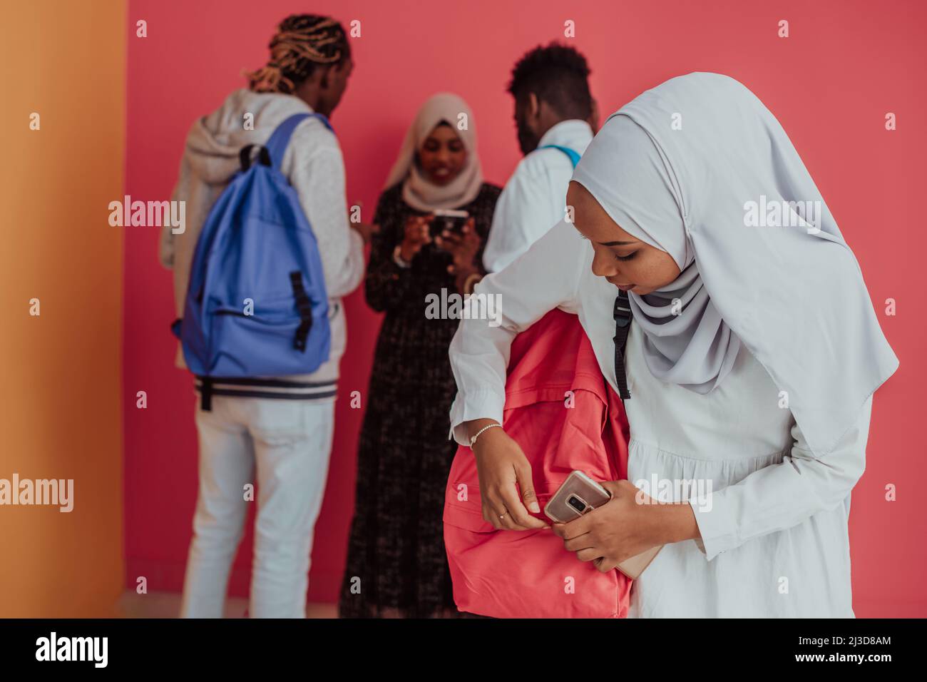 A group of African Muslim students with backpacks posing on a pink ...