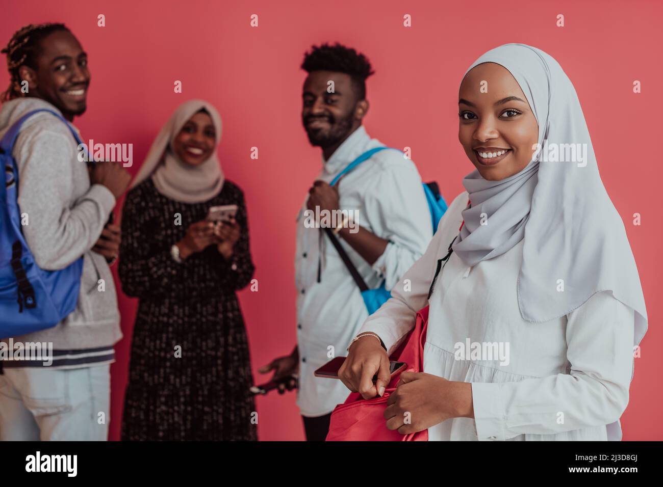 A group of African Muslim students with backpacks posing on a pink ...