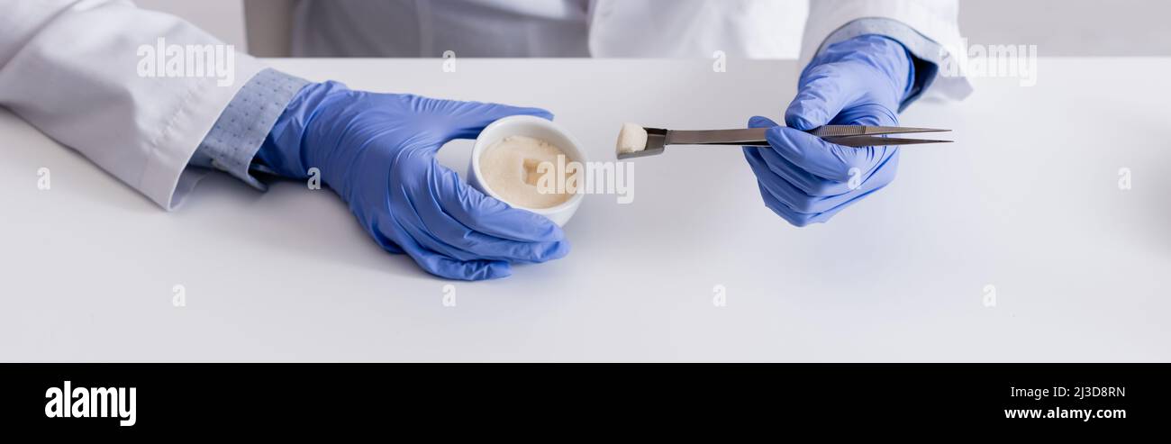 cropped view of chemist in latex gloves holding tweezers and bowl with ...