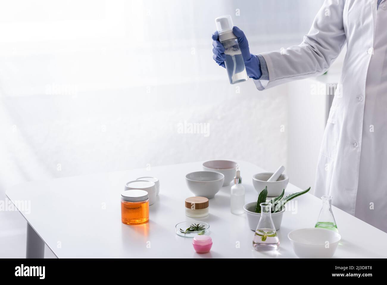 partial view of laboratory assistant in latex glove holding bottle with ...