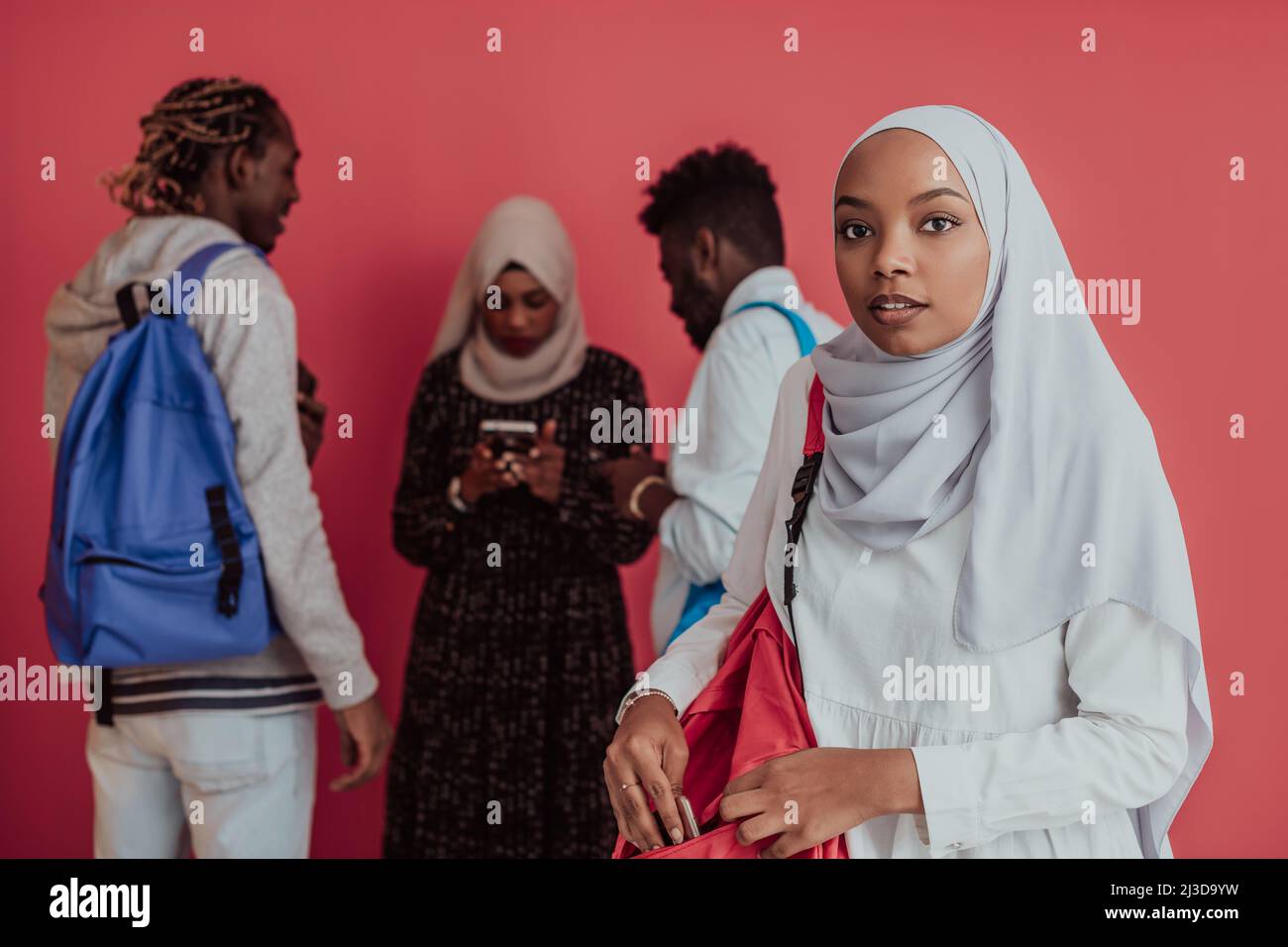 A group of African Muslim students with backpacks posing on a pink ...