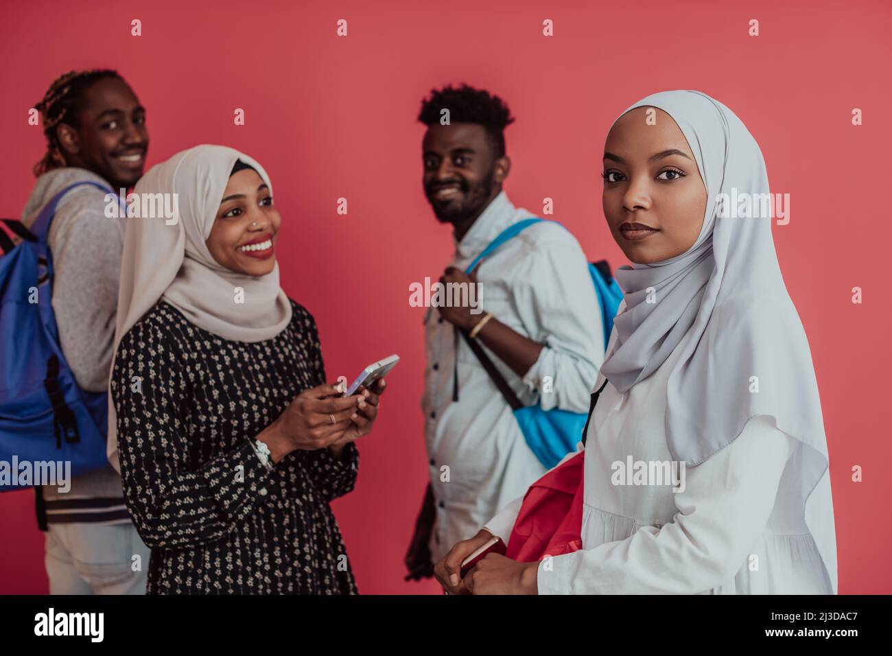 A group of African Muslim students with backpacks posing on a pink ...