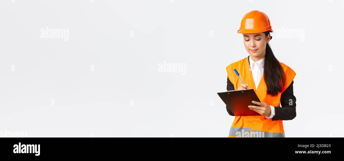 Pleased asian female construction engineer, architect taking notes in ...