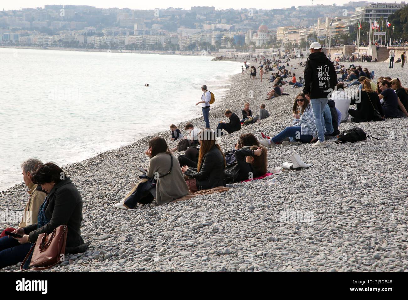 People seen sitting on the gravel beach on Plage du Centenaire on the ...