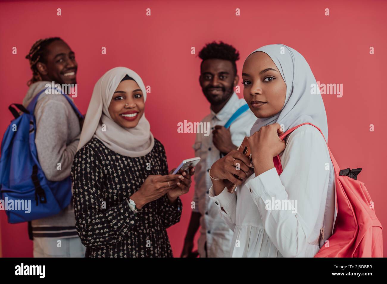 A group of African Muslim students with backpacks posing on a pink ...