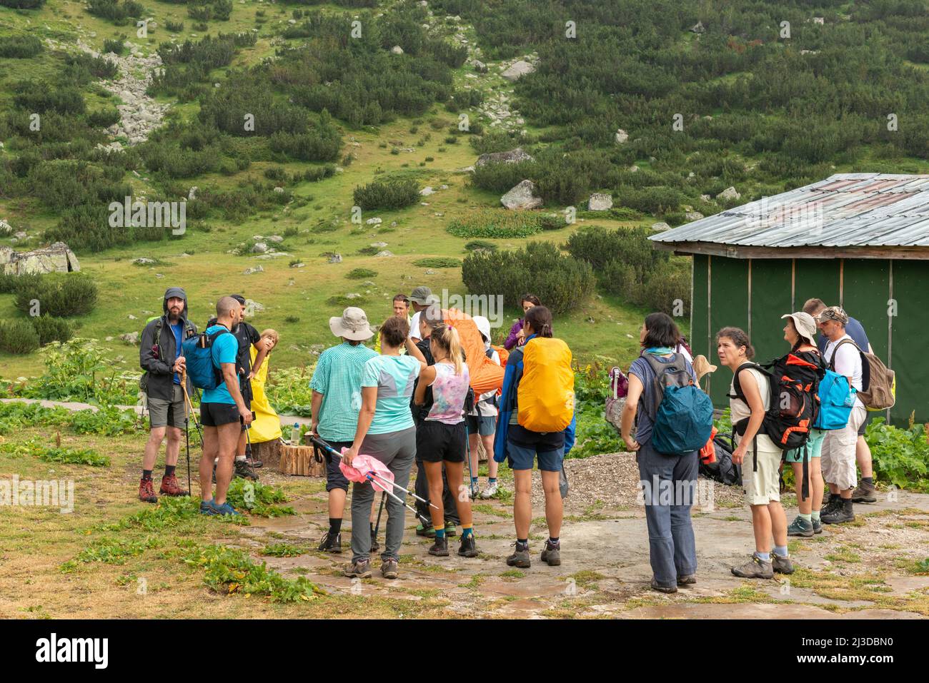 Mixed group of hikers gathering together at a mountain hut after ...