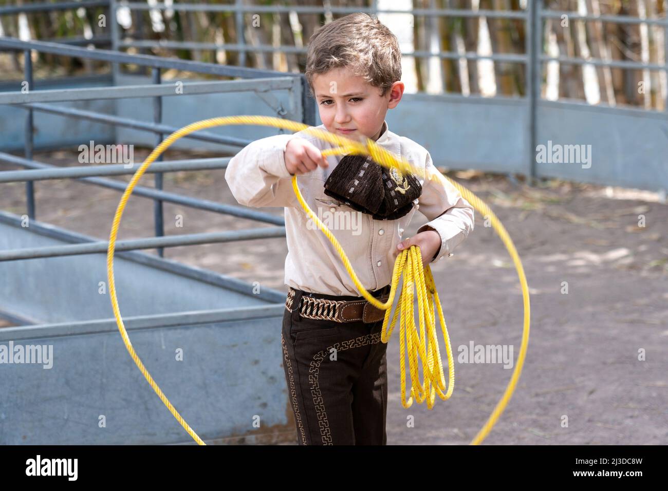 A Young Mexican boy wearing a charro outfit, shows off his roping ...