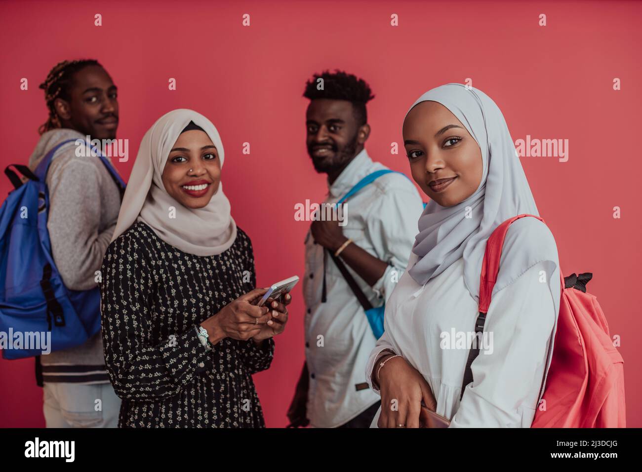 A group of African Muslim students with backpacks posing on a pink ...
