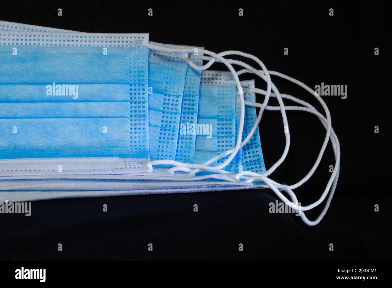 new blue and white surgical masks isolated on a black background with ...