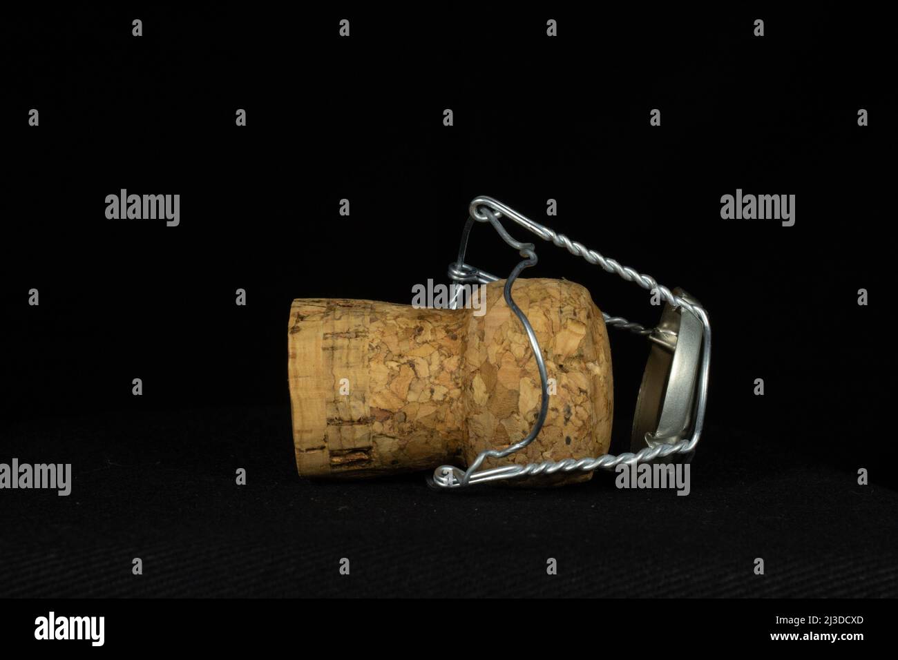 sparkling wine cork inside a wire cage isolated on a black background ...