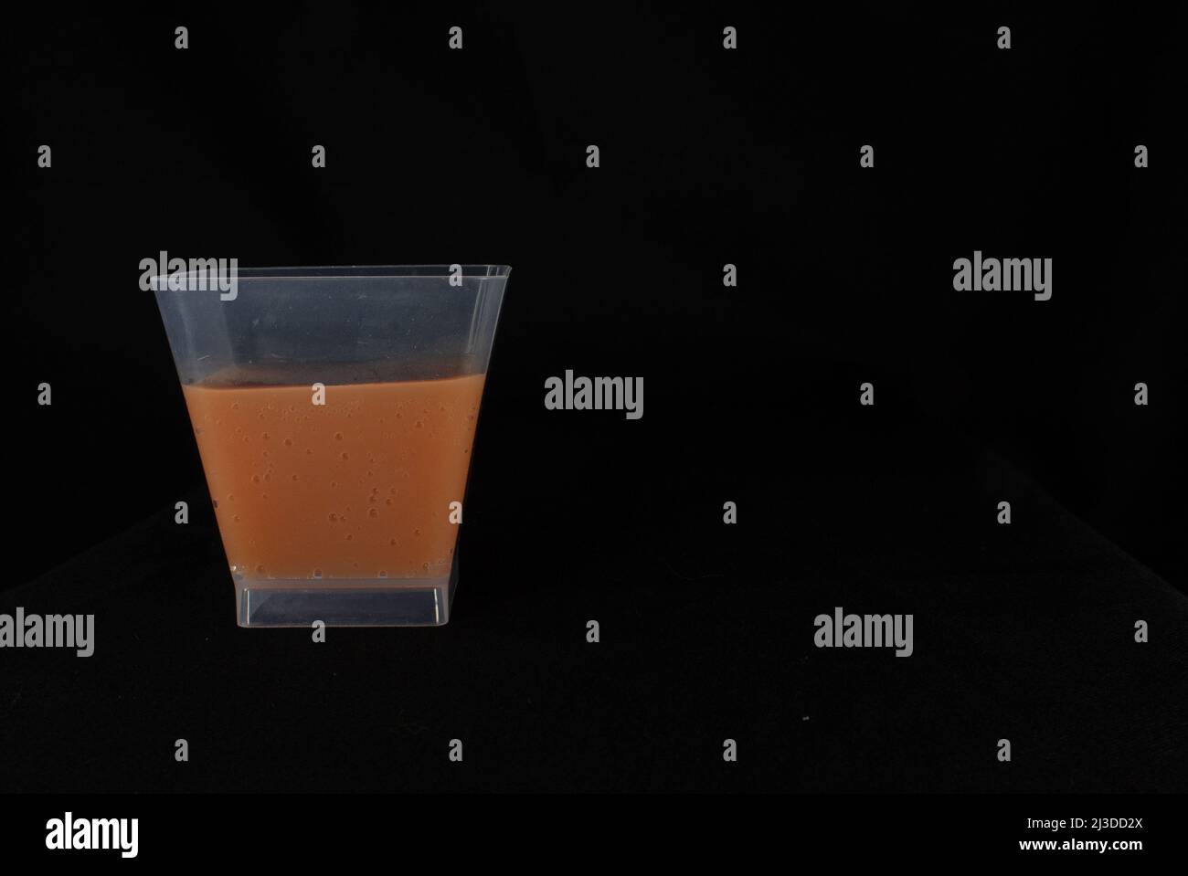 two plastic cups half full of liquid isolated on a black background ...
