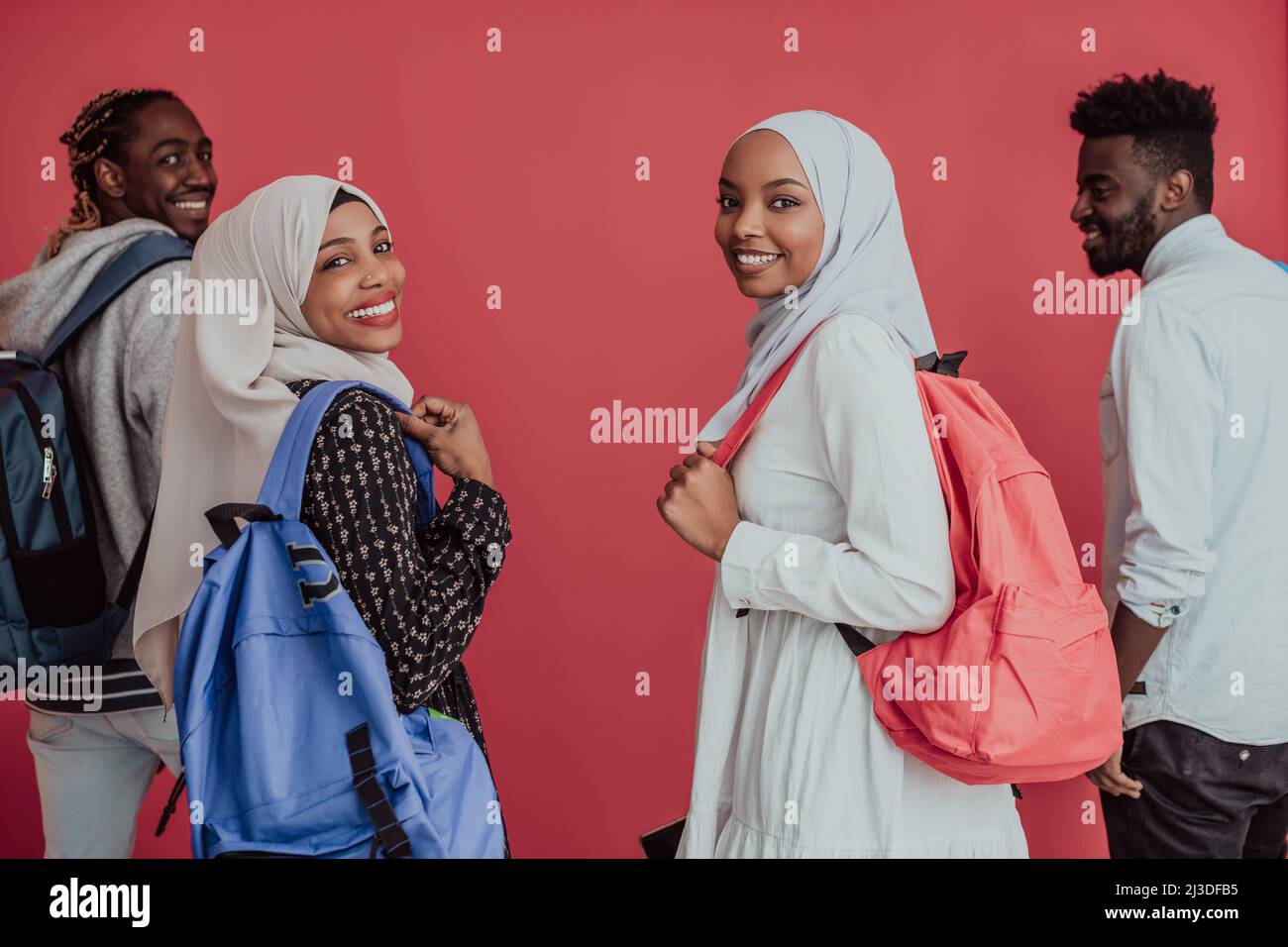 A group of African Muslim students with backpacks posing on a pink ...