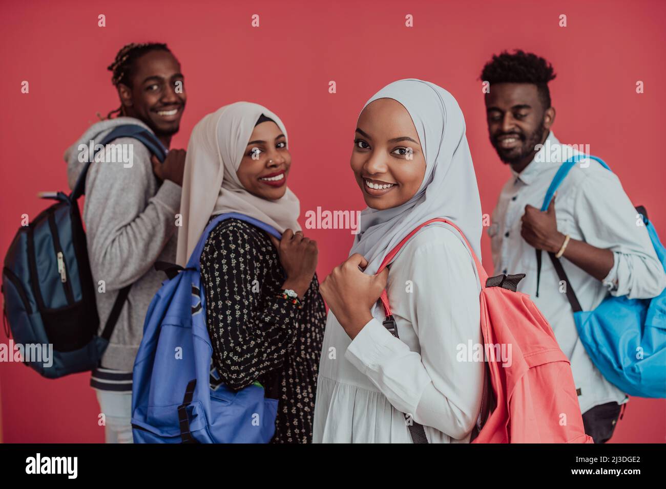 A group of African Muslim students with backpacks posing on a pink ...