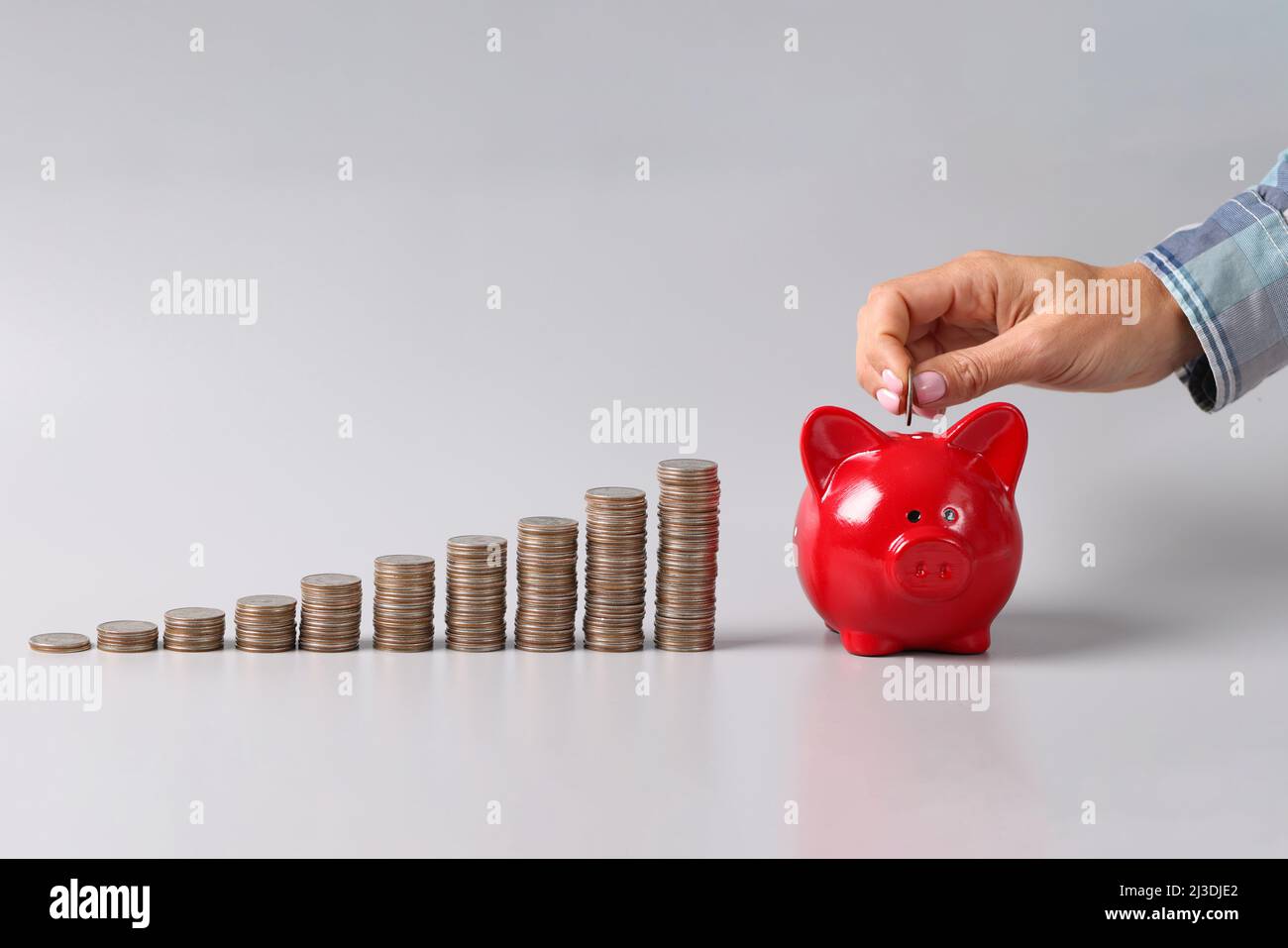 Stacks of rising financial coins and piggy bank person throws coin ...